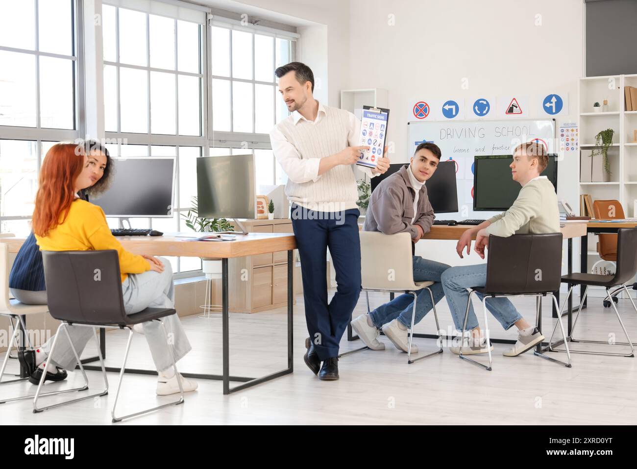 Male instructor with traffic signs giving lesson to people at driving ...