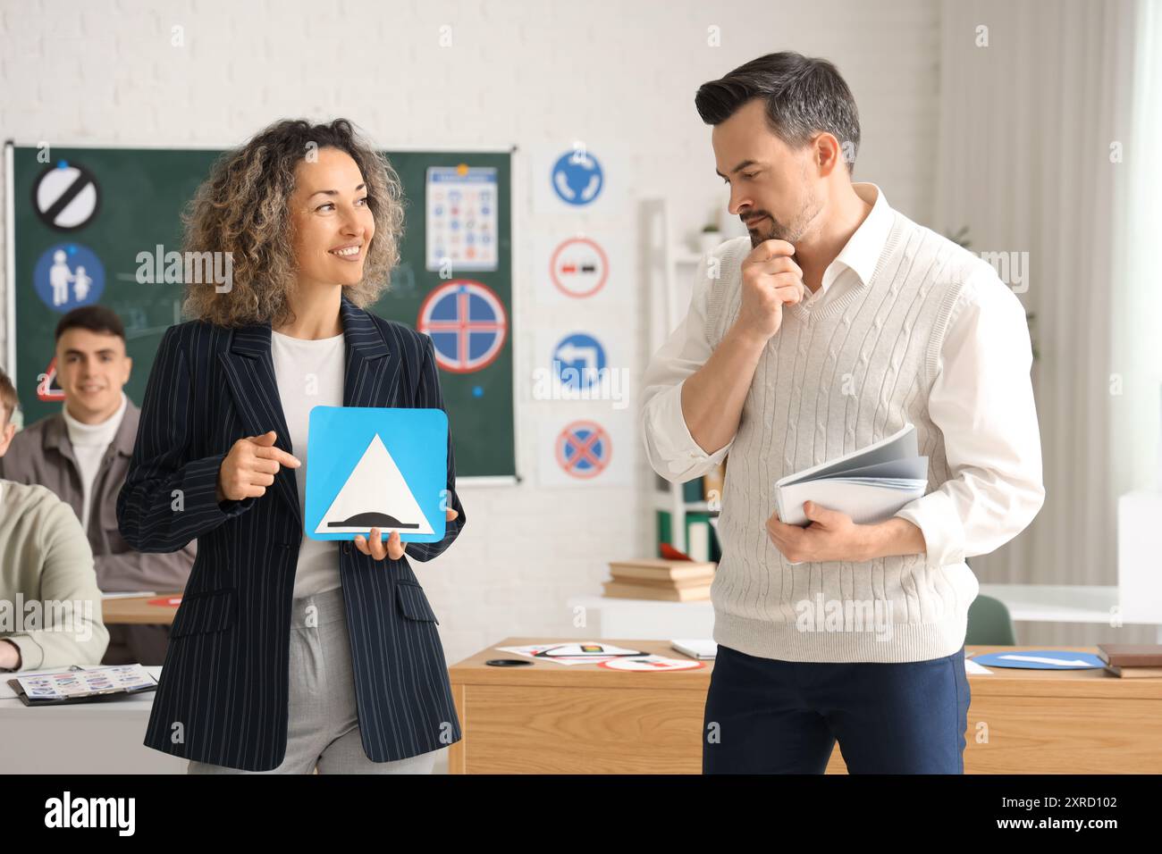 Female instructor with road sign and man at driving school Stock Photo ...