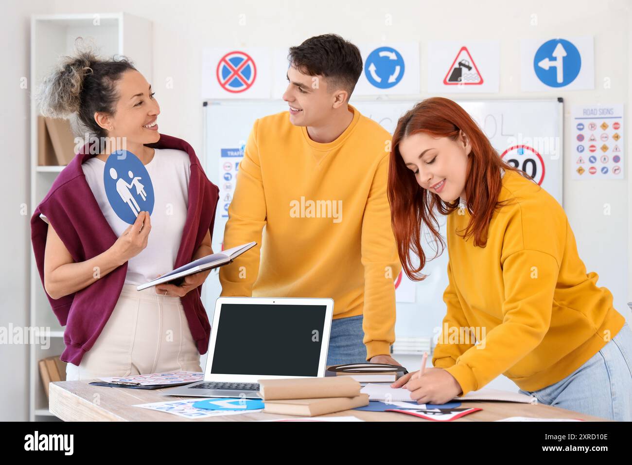 Female instructor with road sign giving lesson to people at driving ...