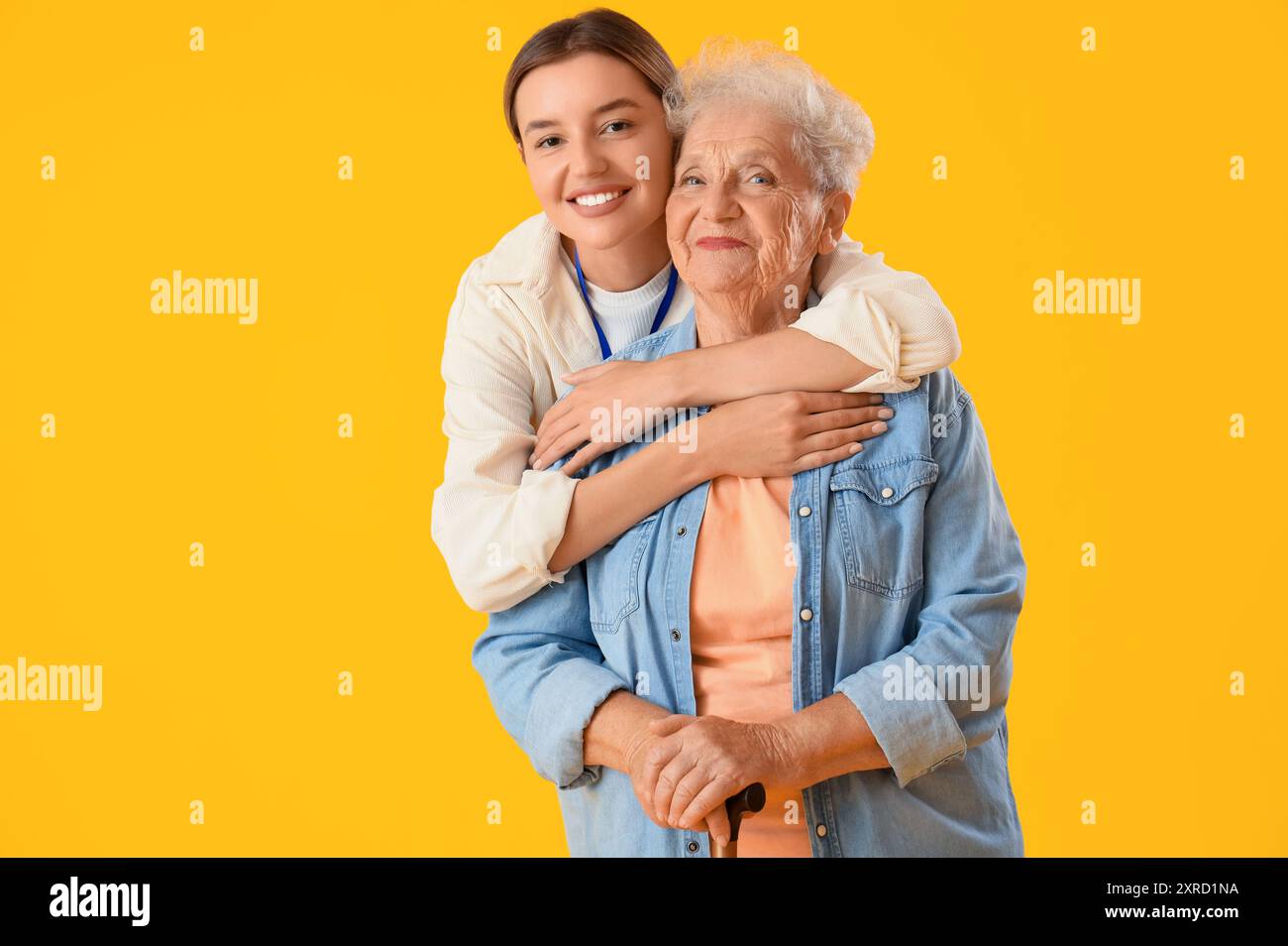 Nurse hugging senior woman on yellow background Stock Photo - Alamy