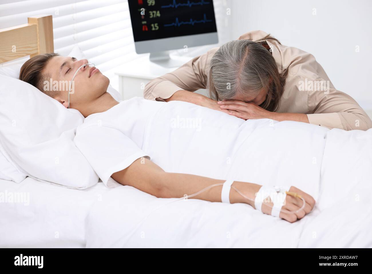Coma patient. Sad mature woman near her unconscious son in hospital ...