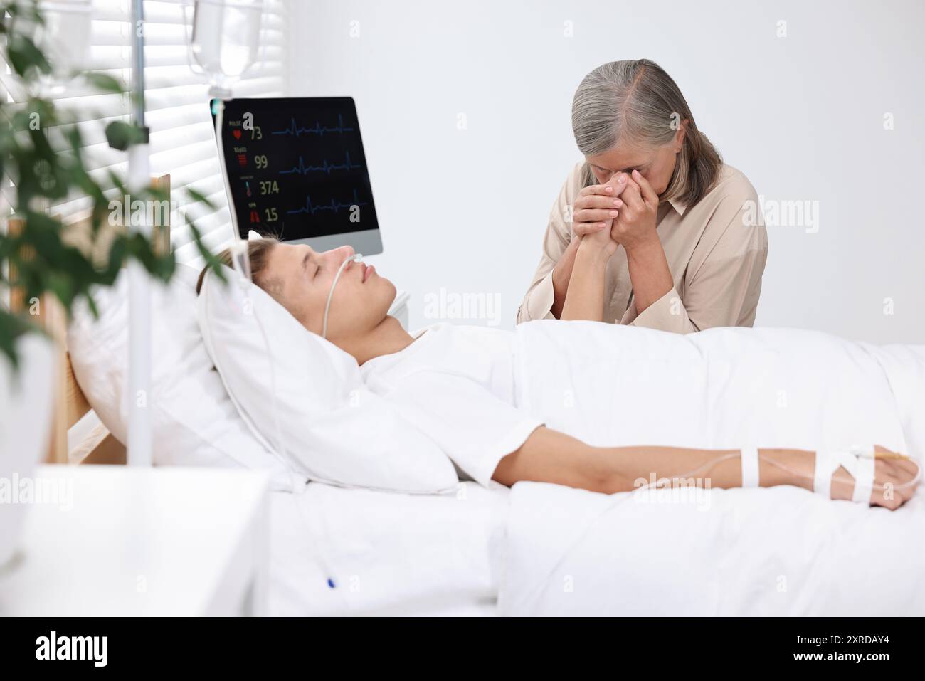 Coma patient. Sad mature woman near her unconscious son in hospital ...