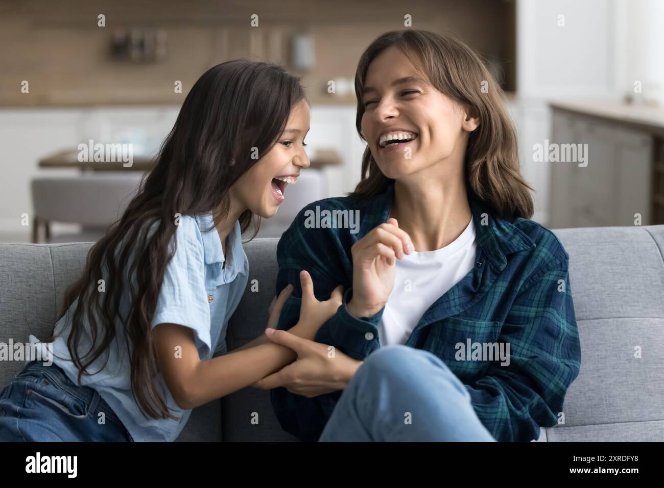 Excited active kid tickling cheerful laughing young mom on sofa Stock ...