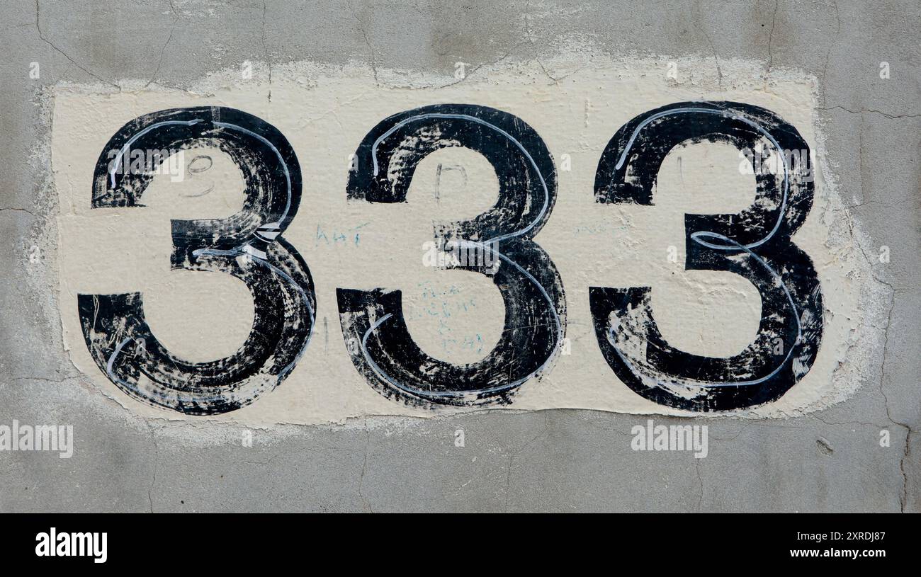 a worn sign featuring the number 333 on a concrete wall Stock Photo - Alamy