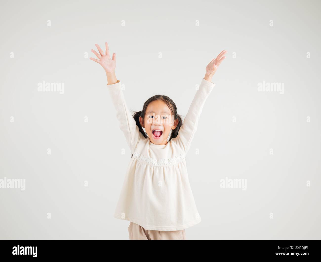 A jubilant kid girl raises her fists in celebration of her success ...