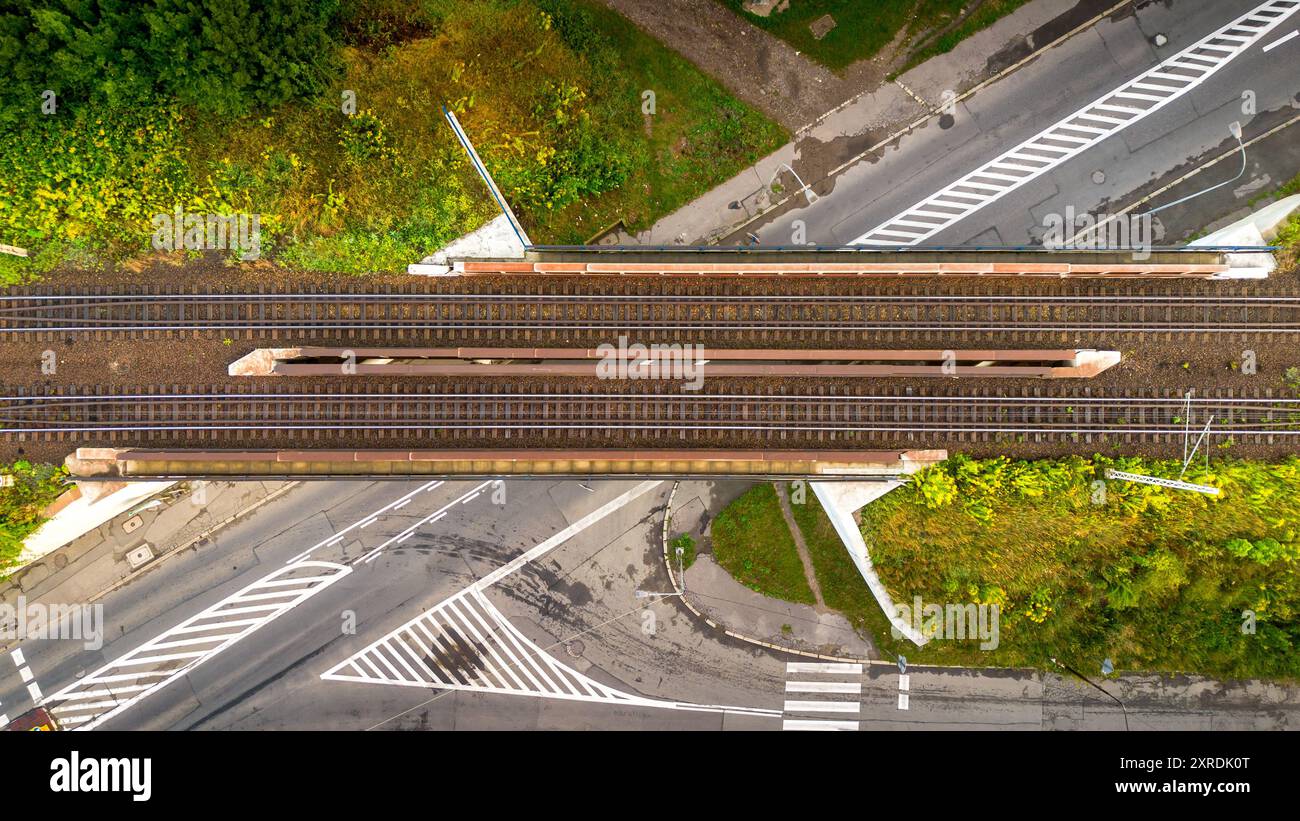 Aerial view of railway tracks crossing a road in a rural area during ...