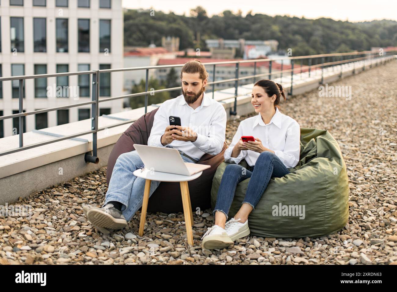 Two people working remotely with gadgets on rooftop Stock Photo - Alamy