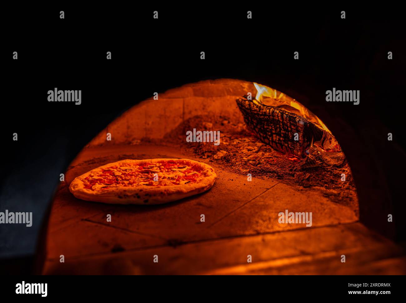 Baking pizza in the oven with burning fire. Pizza cooked in a wood oven ...