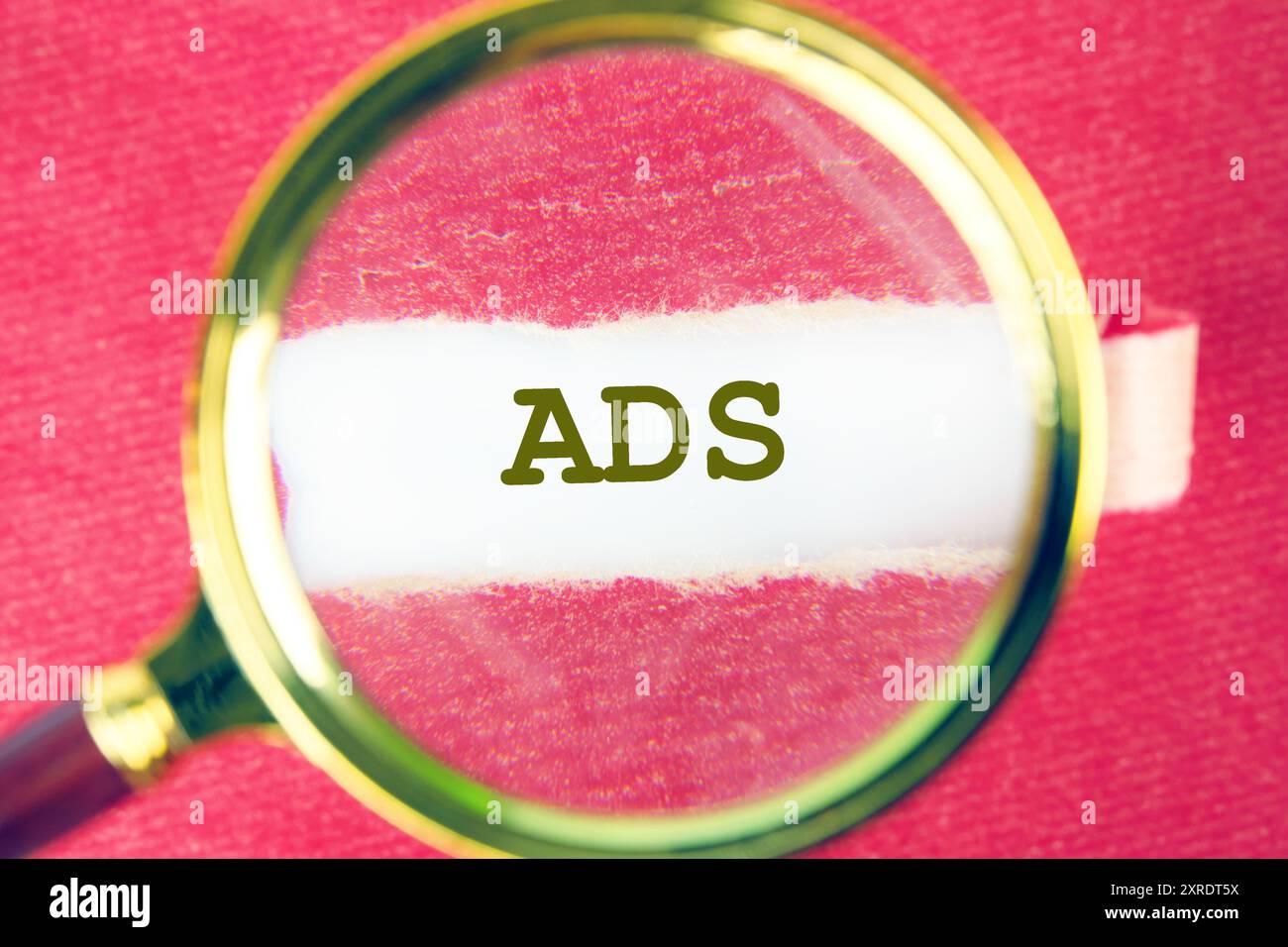 Abbreviation ADS written through a magnifying glass under a torn paper ...