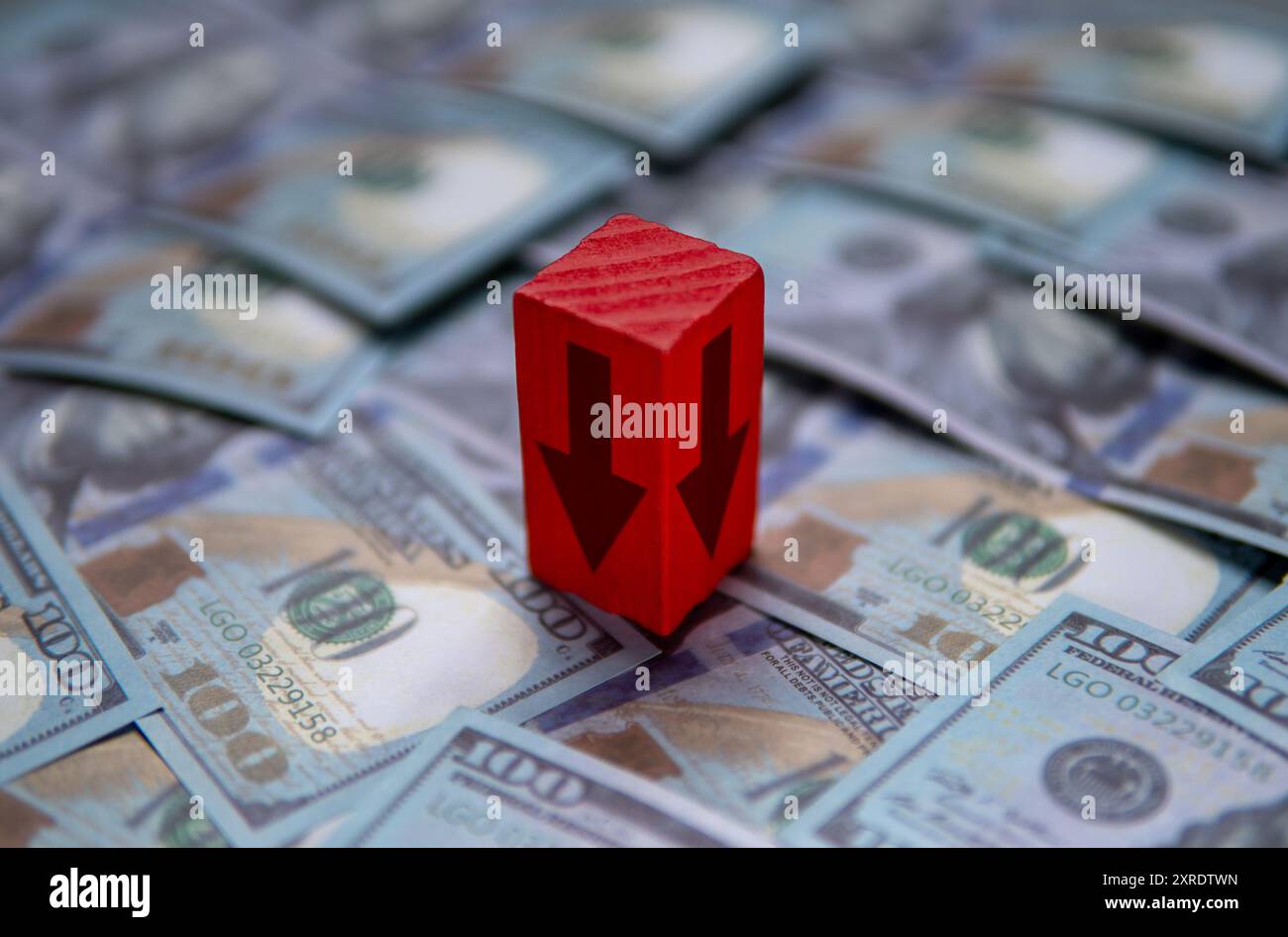 A red arrow pointing downwards on top of a pile of US dollar bills ...