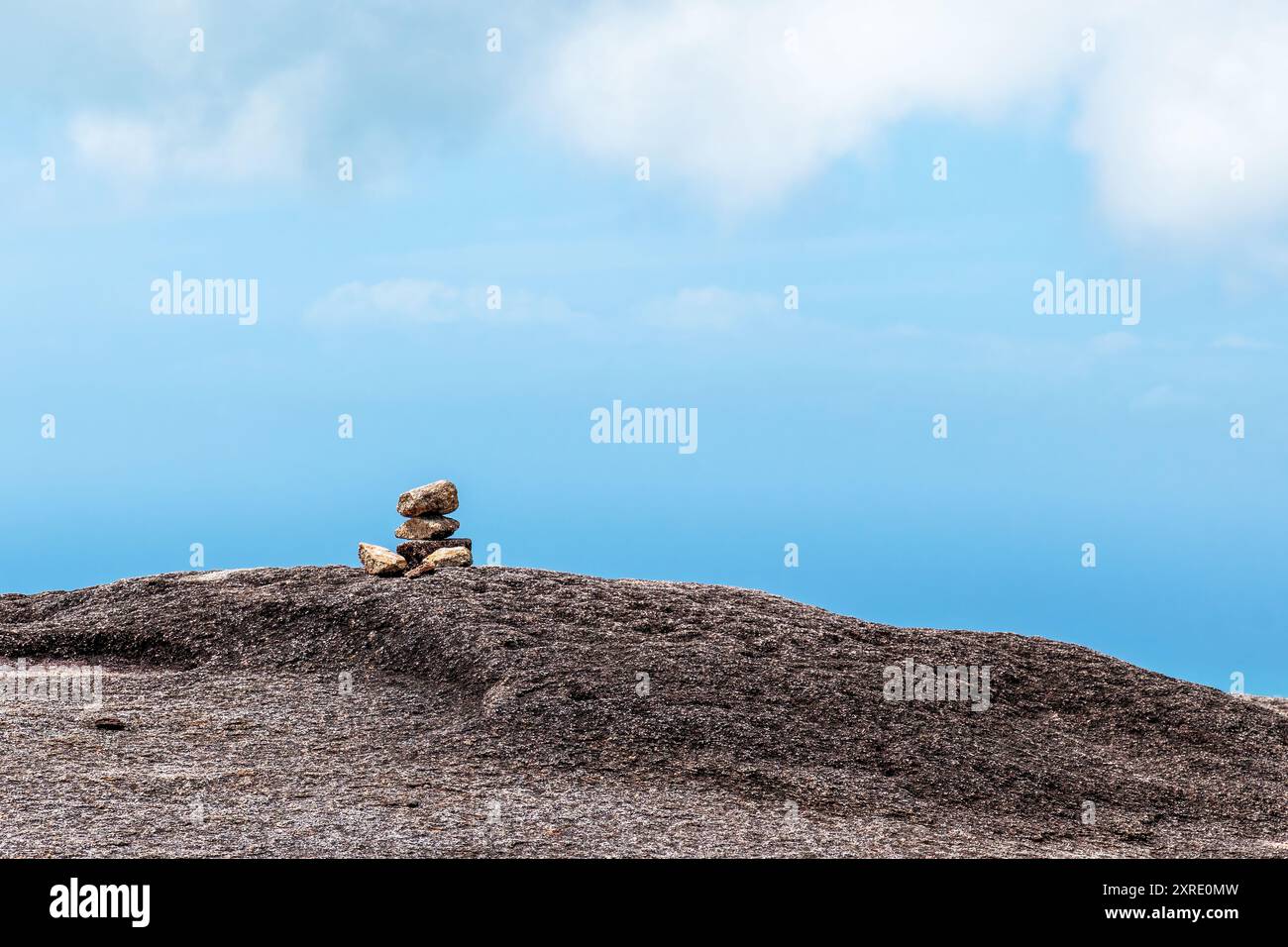 Small cairn of stones sits atop a rocky hill, with a clear blue sky and ...
