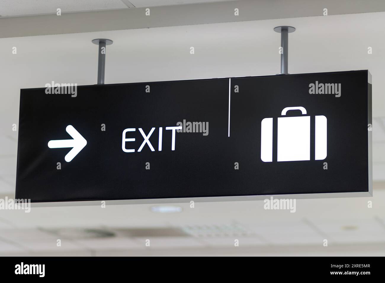 A sign indicating the direction to the exit hangs from the ceiling of ...