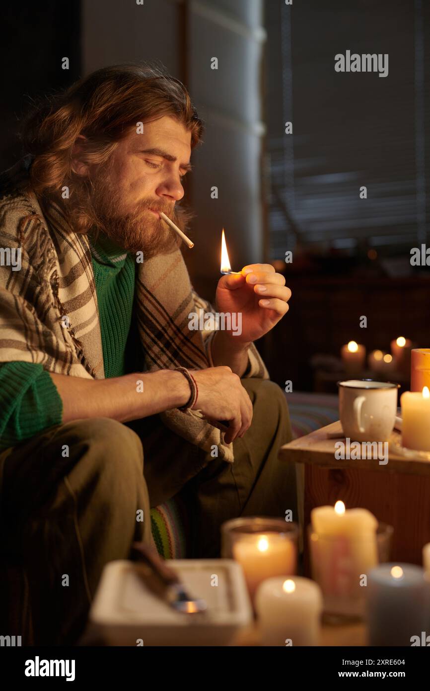 Man with a beard sitting in an indoor space surrounded by lit candles ...