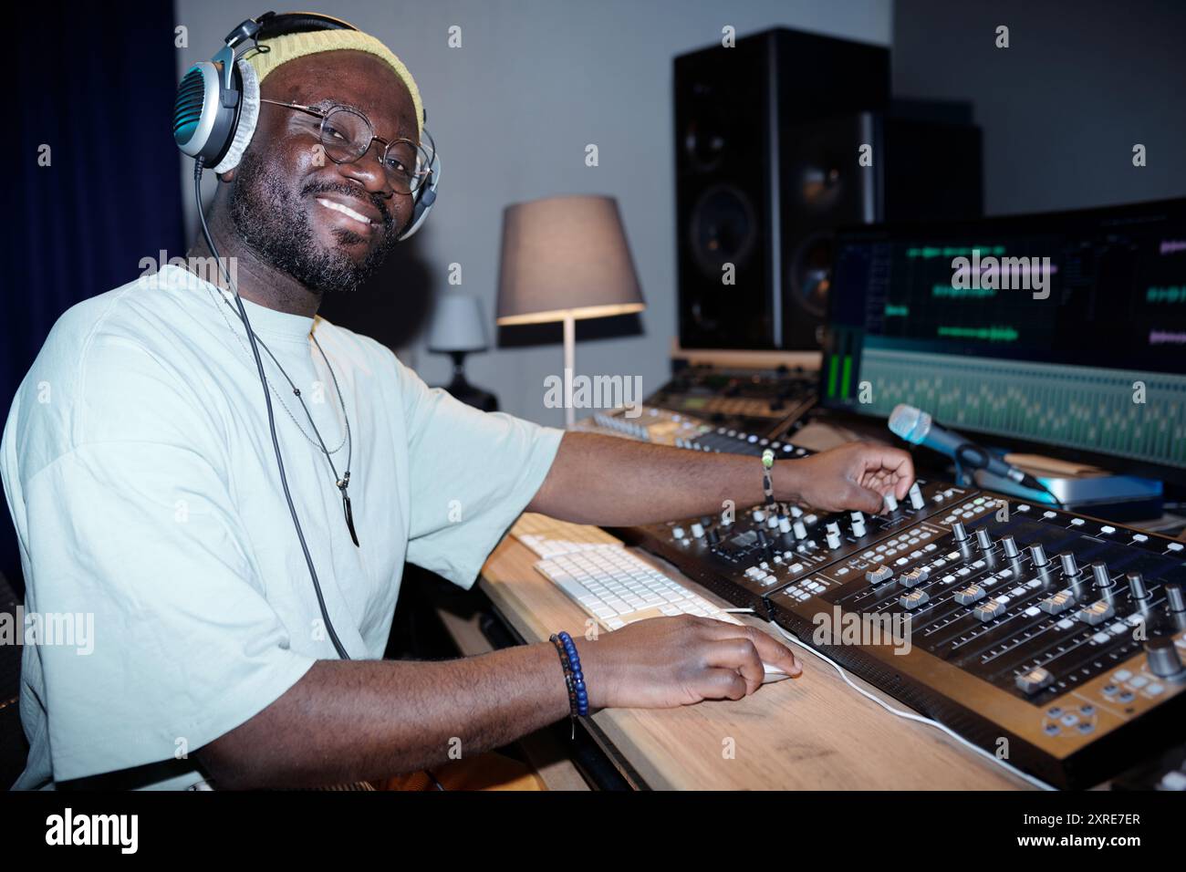 Man wearing headphones, smiling while using professional sound mixing ...