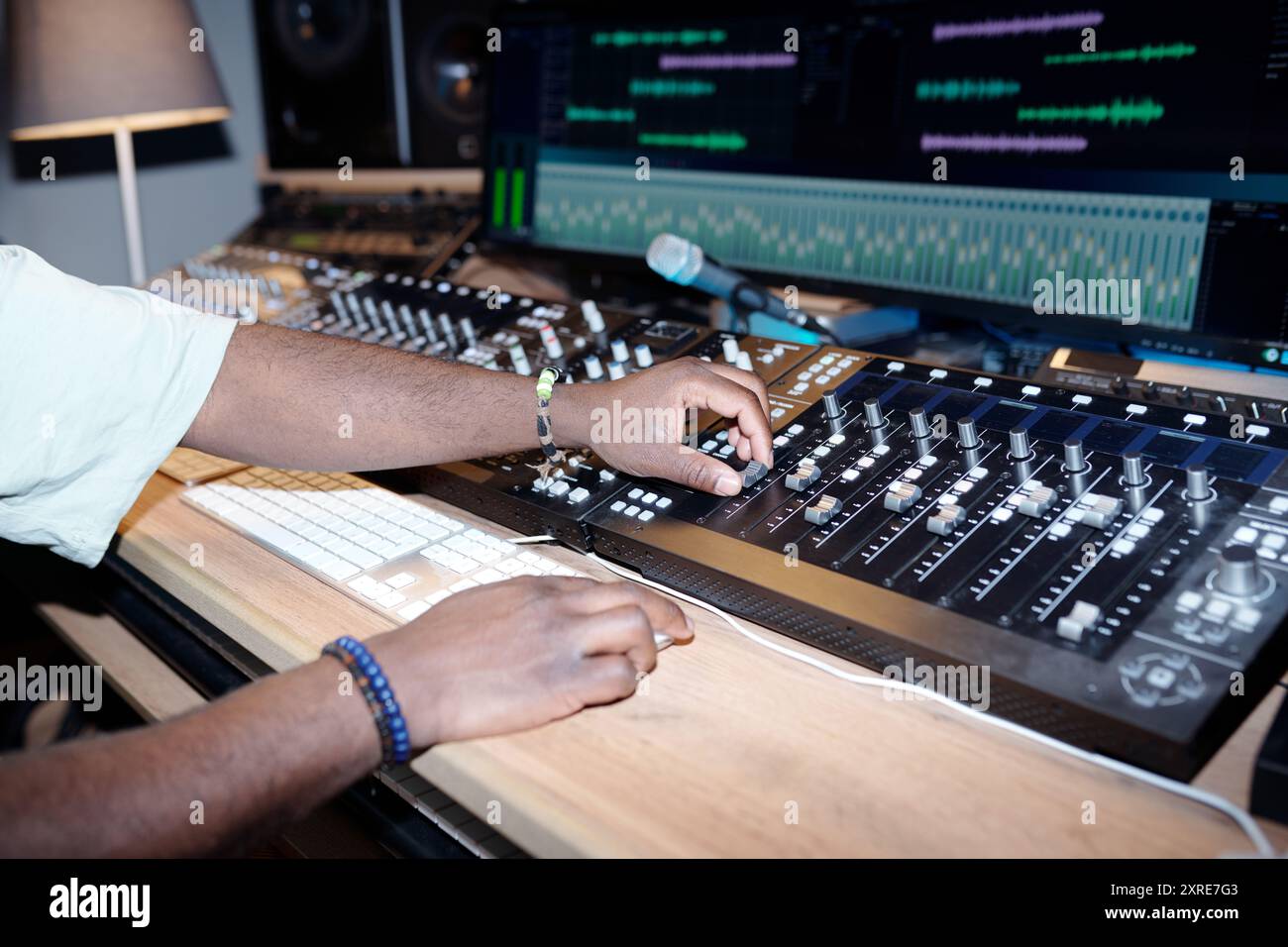 Person's hand adjusting audio levels on mixing console with multiple ...