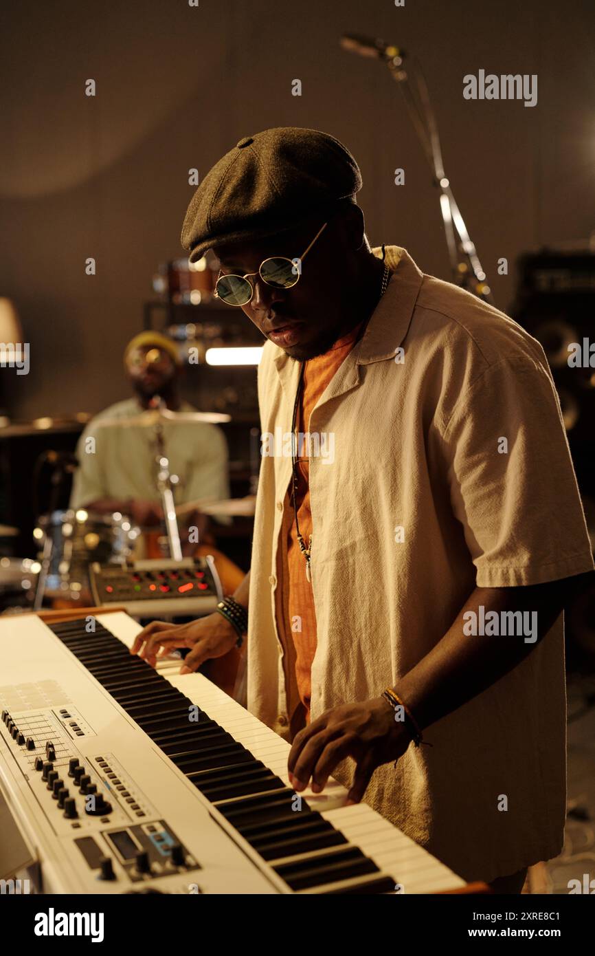 African American musician playing keyboard in music studio setting ...
