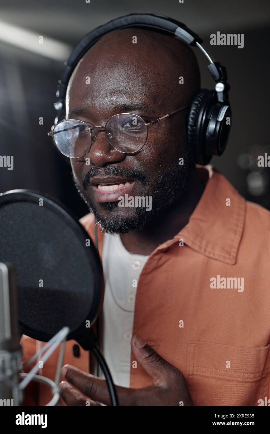Portrait of African American man wearing headphones, holding microphone ...