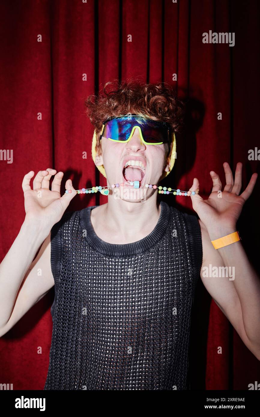 Young excited man in stylish attire and sunglasses holding neck ...