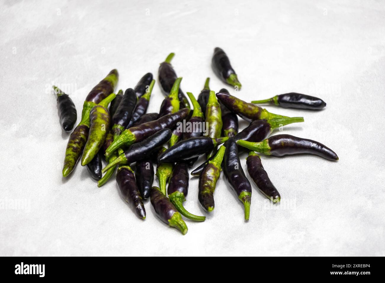 Fresh black chillies on white background Stock Photo - Alamy