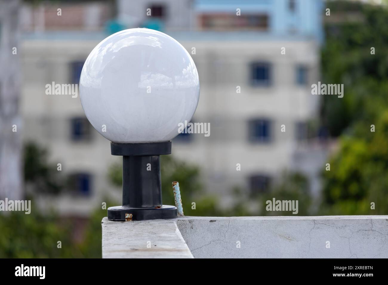 White round glass lamp on a black steel pole on white wall in house ...