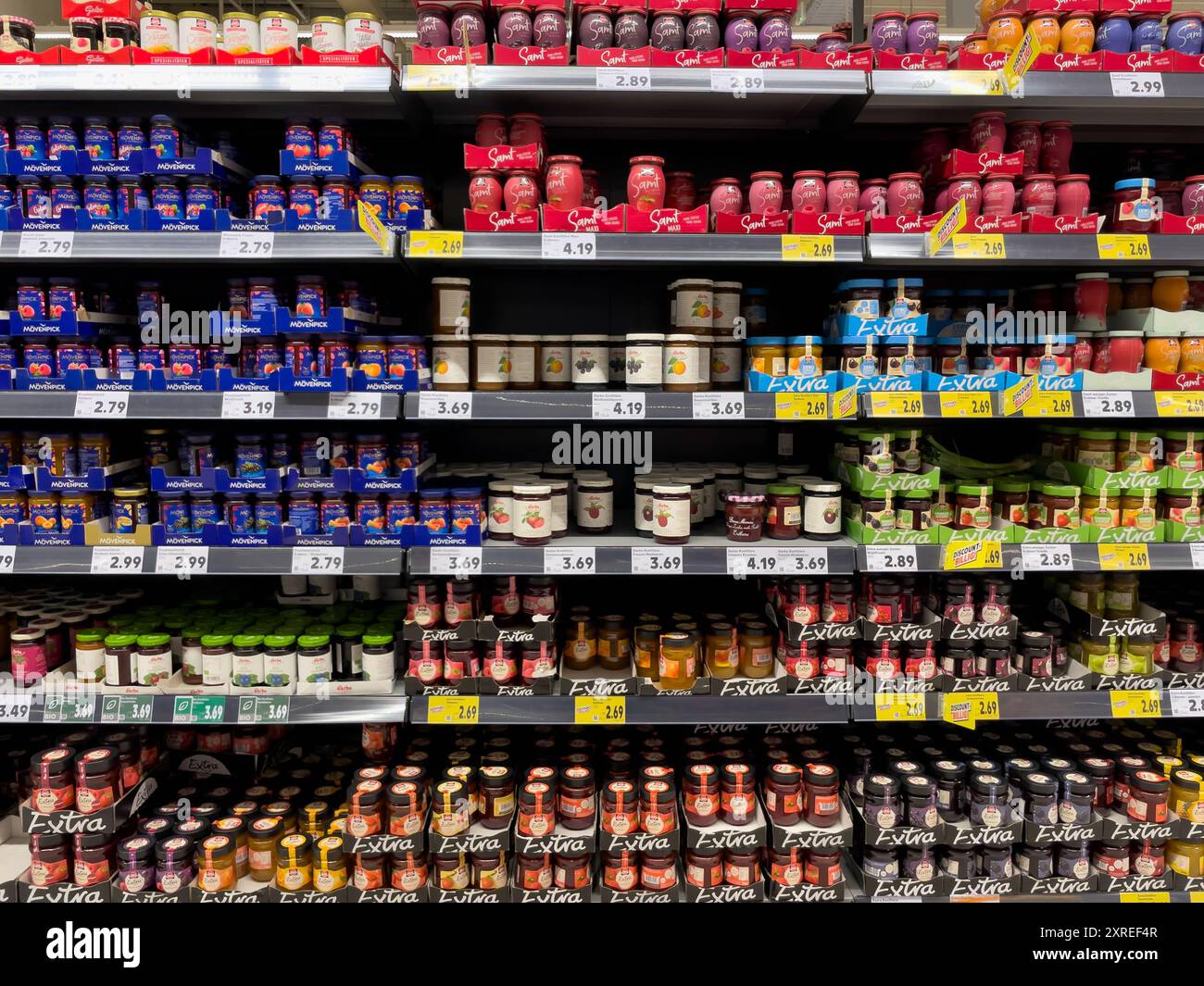 There are rows of jars and bottles of jam on the shelf. Jars come in ...