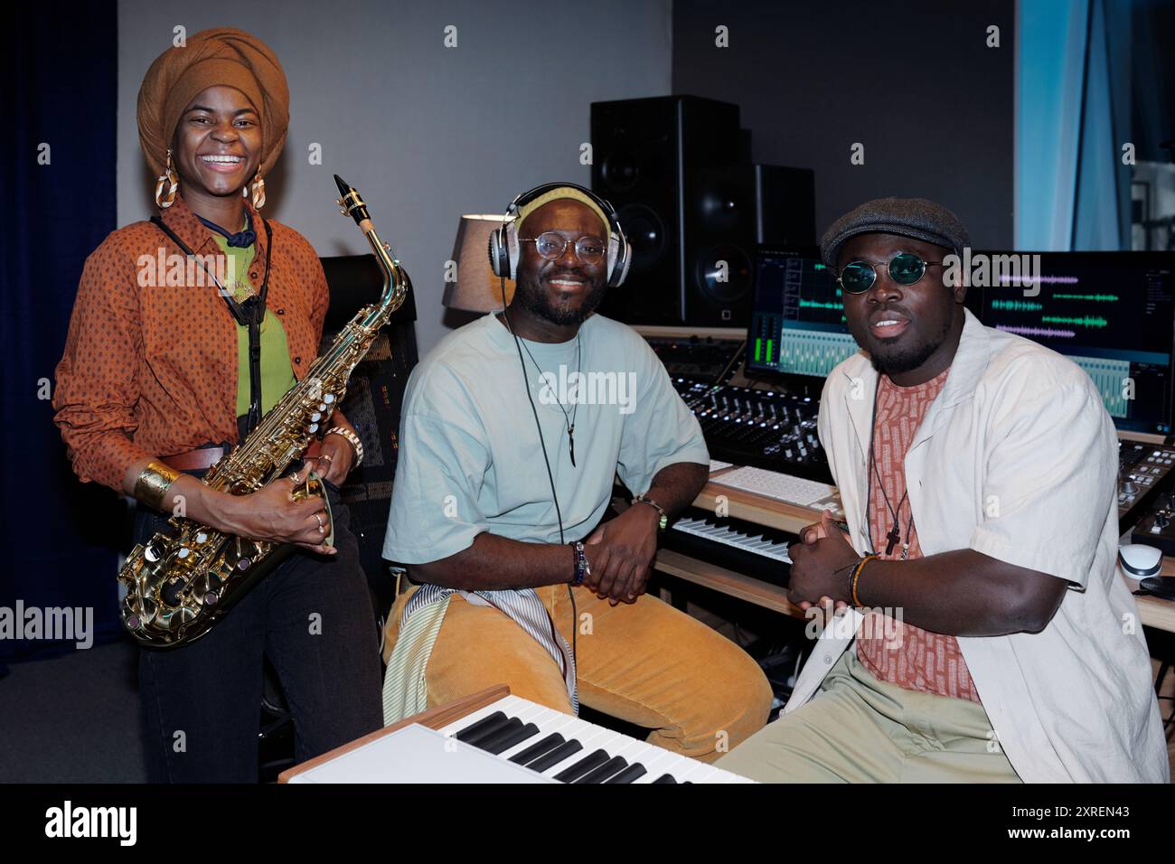 Three African American musicians smiling while working in modern ...