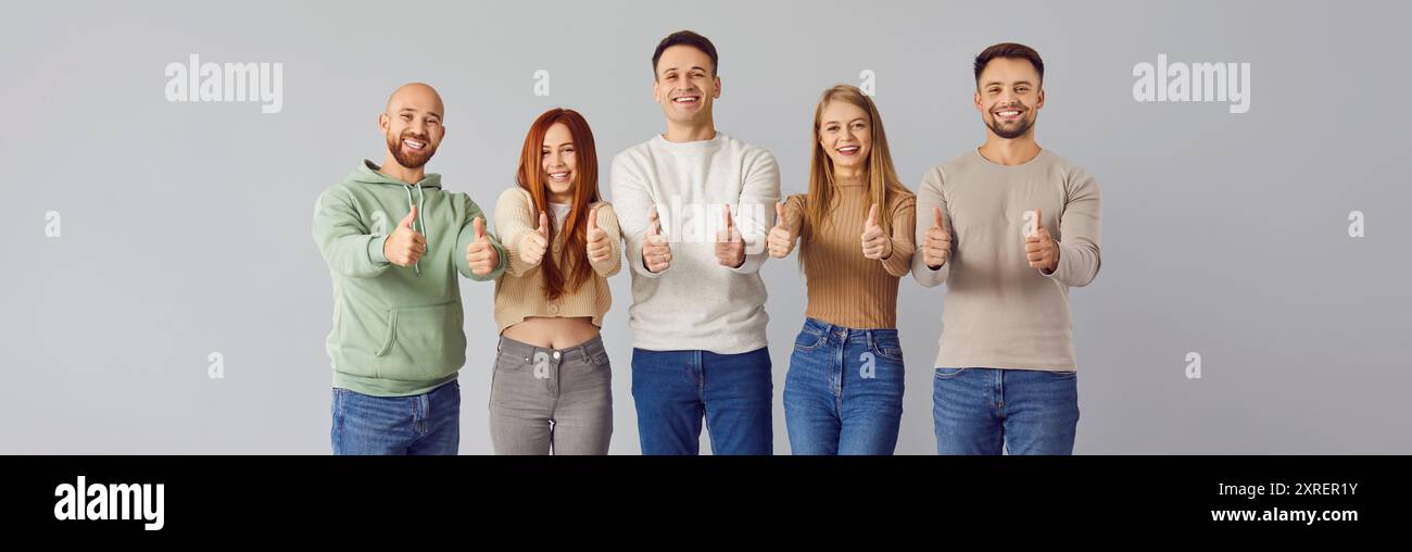 Group portrait of young happy people standing showing thumb up gesture ...