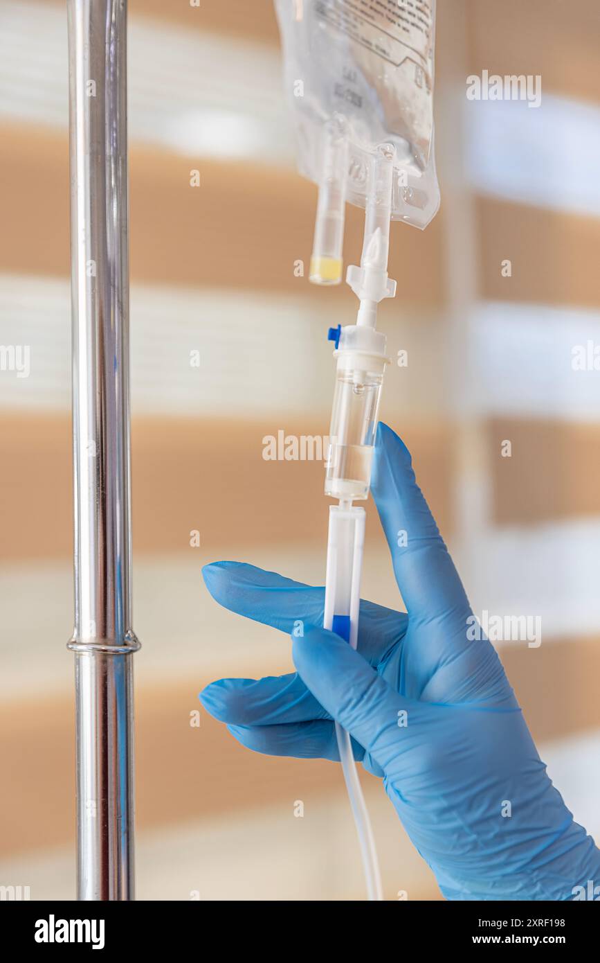 Nurse connecting an IV drip. Nurse preparing and regulating infusion for patient in hospital ...