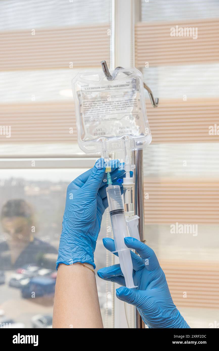 Nurse connecting an IV drip. Nurse preparing and regulating infusion for patient in hospital ...