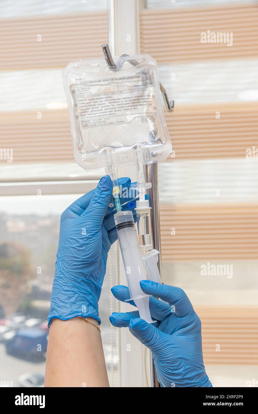 Nurse connecting an IV drip. Nurse preparing and regulating infusion for patient in hospital ...
