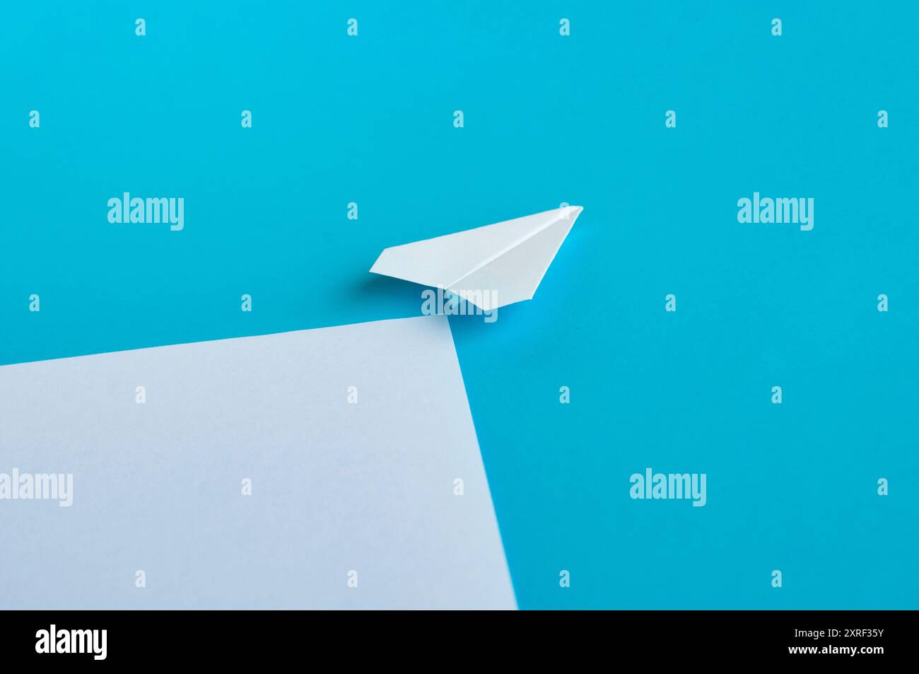 Angle view of white paper airplane flying along the route on blue ...