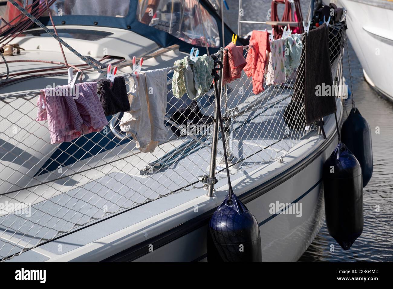 Laundry hangs to dry in the sun on the railing net of a cabin yacht. Sustainable way of drying ...