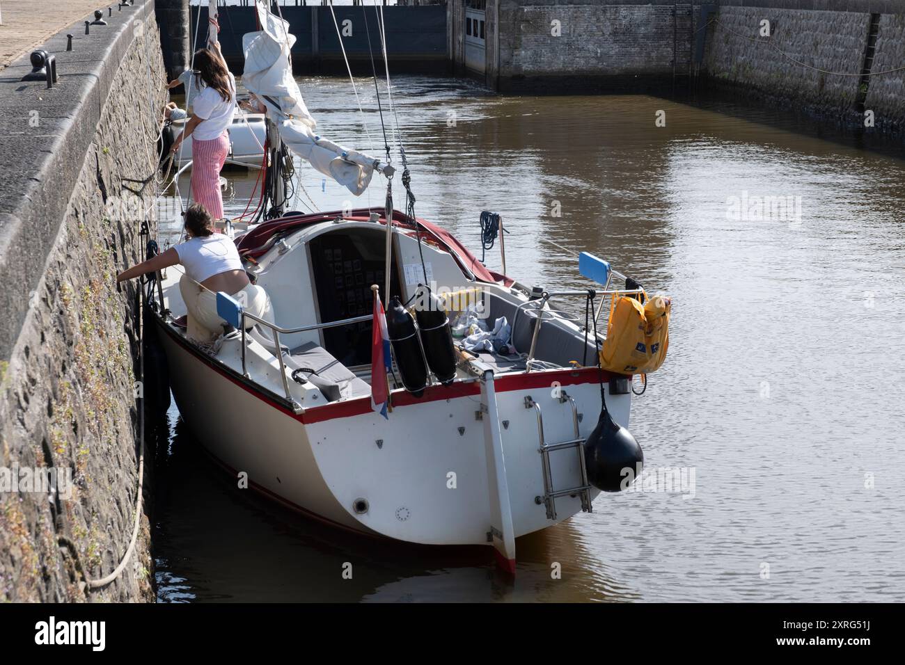 Two girls keep their boat in position by holding on to a rope or object ...