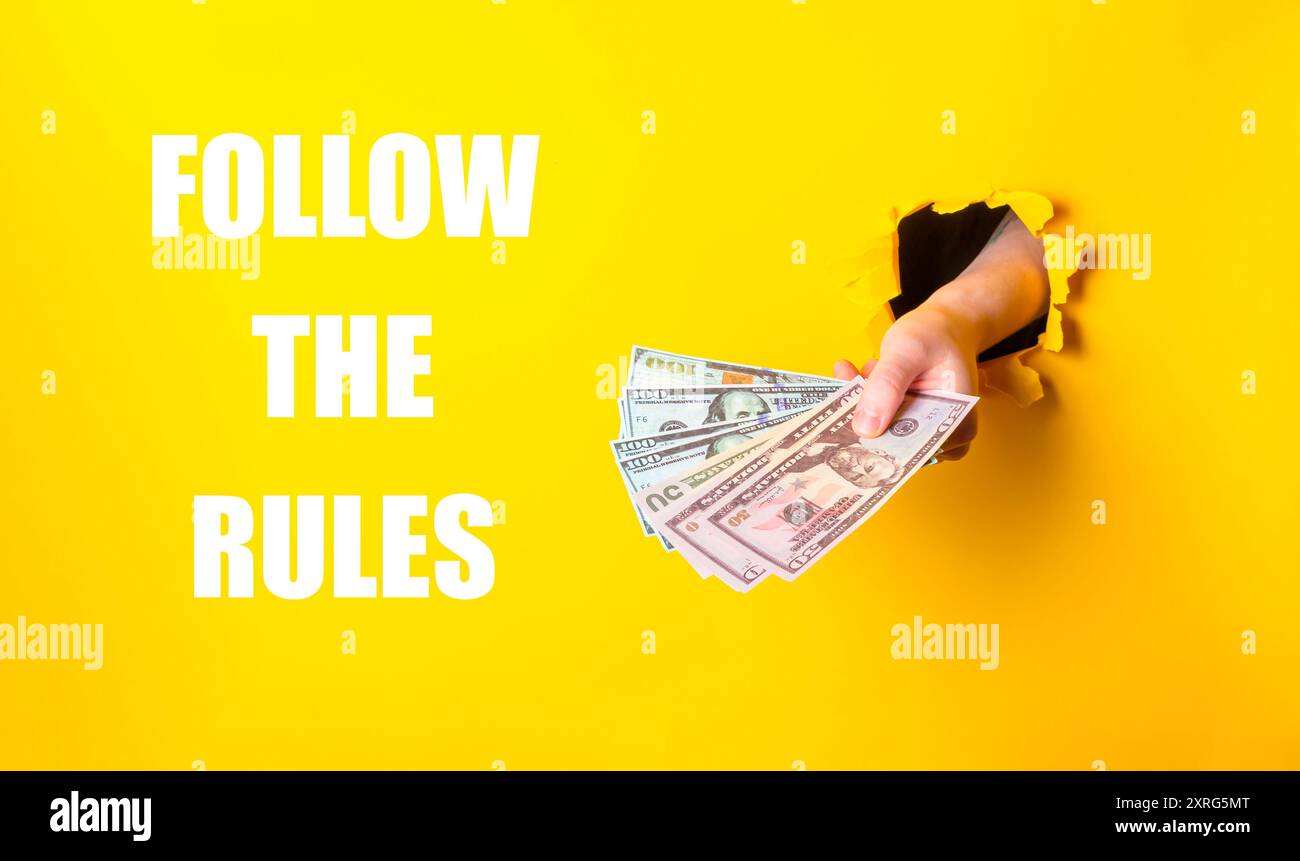 A hand holding a stack of money with the words follow the rules written ...