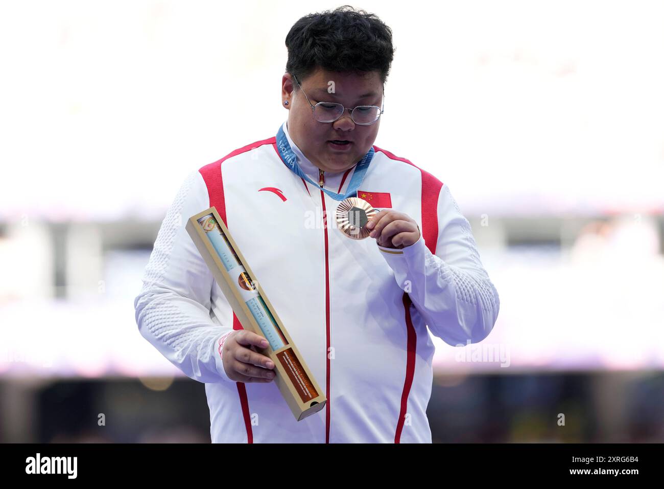 Women's shot put bronze medalist Song Jiayuan, of China, looks at her medal while standing on ...