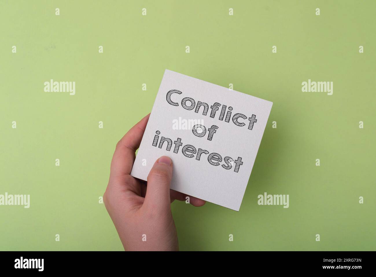 A hand holding a piece of paper with the word conflict of interest ...