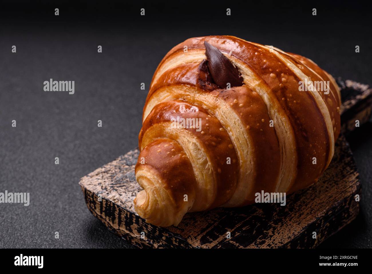 Delicious crispy sweet croissant cornet with chocolate on a dark ...