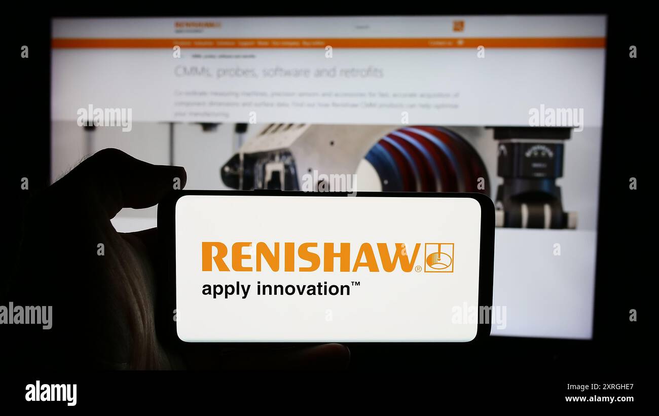 Person holding cellphone with logo of British engineering company Renishaw plc in front of ...