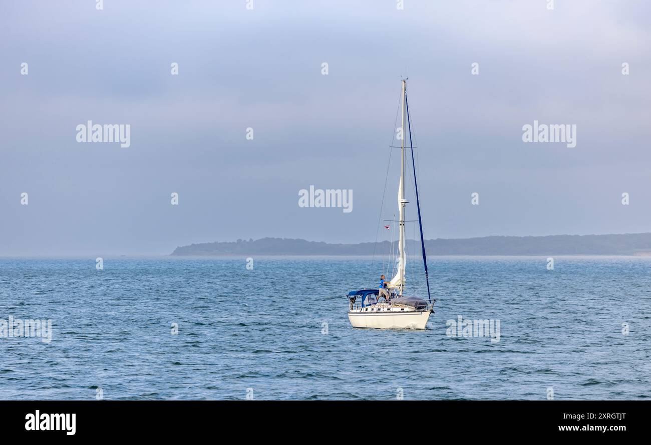 small sail boat with a man working on a sail in gardiners bay Stock ...