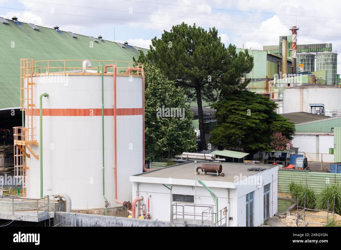 Industrial exterior of a sugar refinery with a large white tank and ...