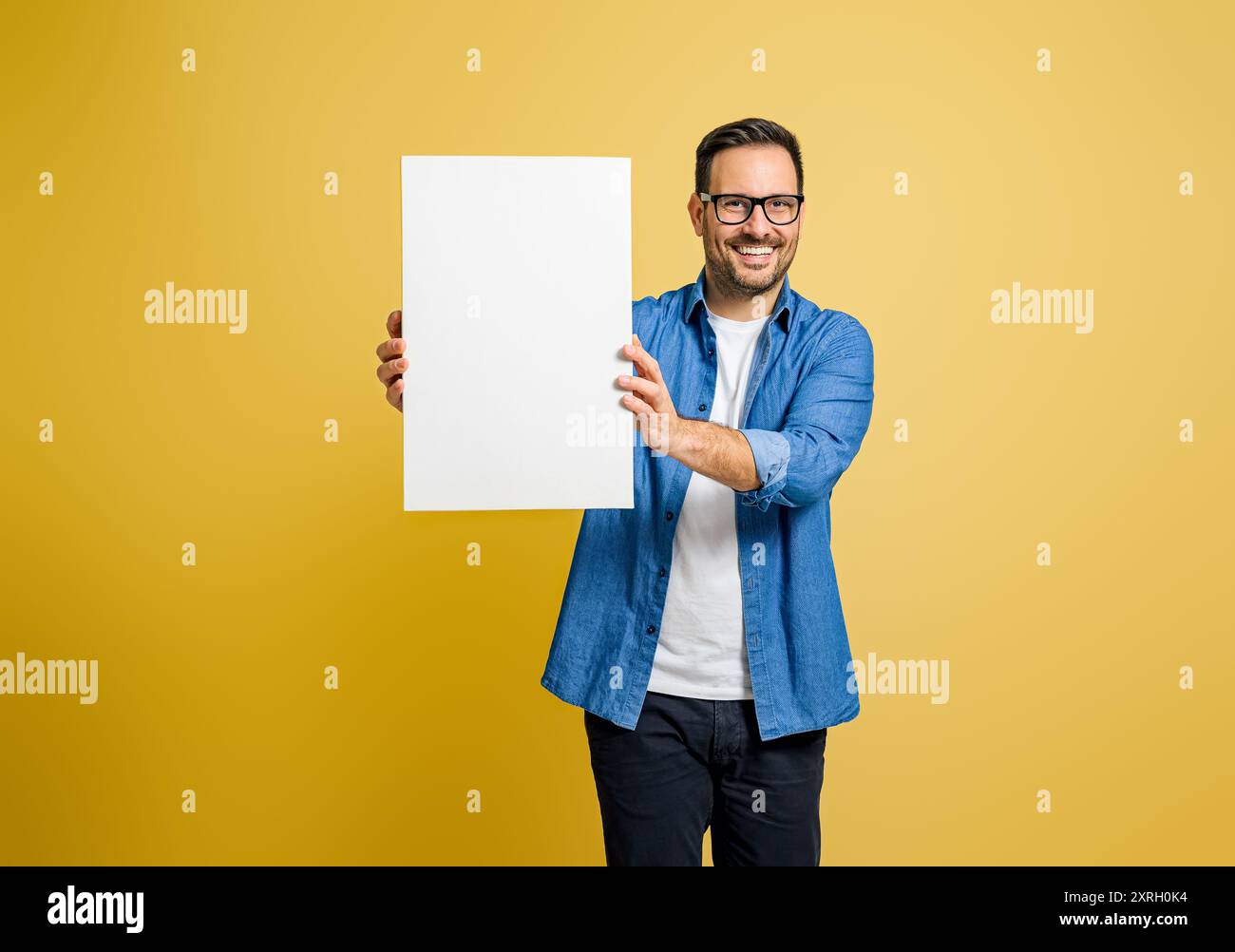 Happy male marketing manager showing blank white poster for advertising ...