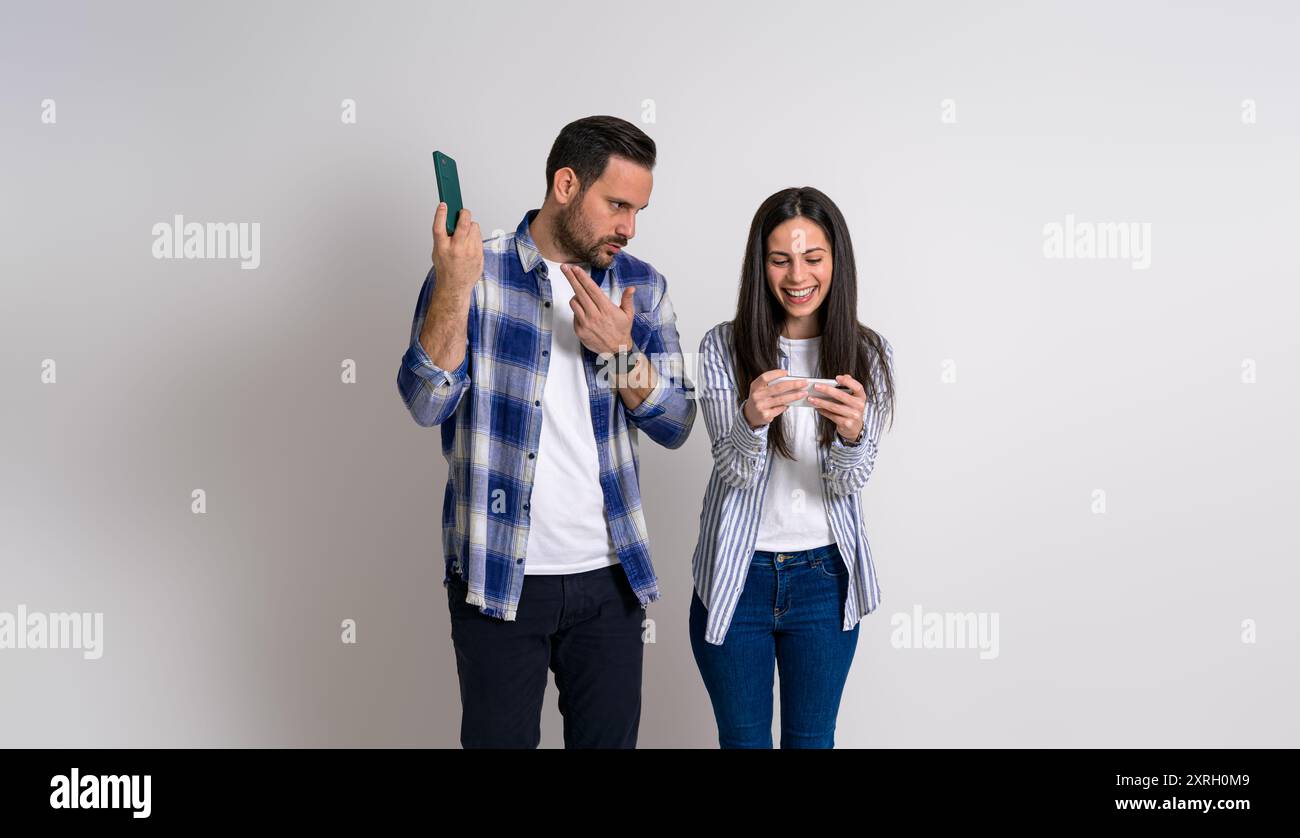Sad young boyfriend gesturing and holding smart phone while excited ...