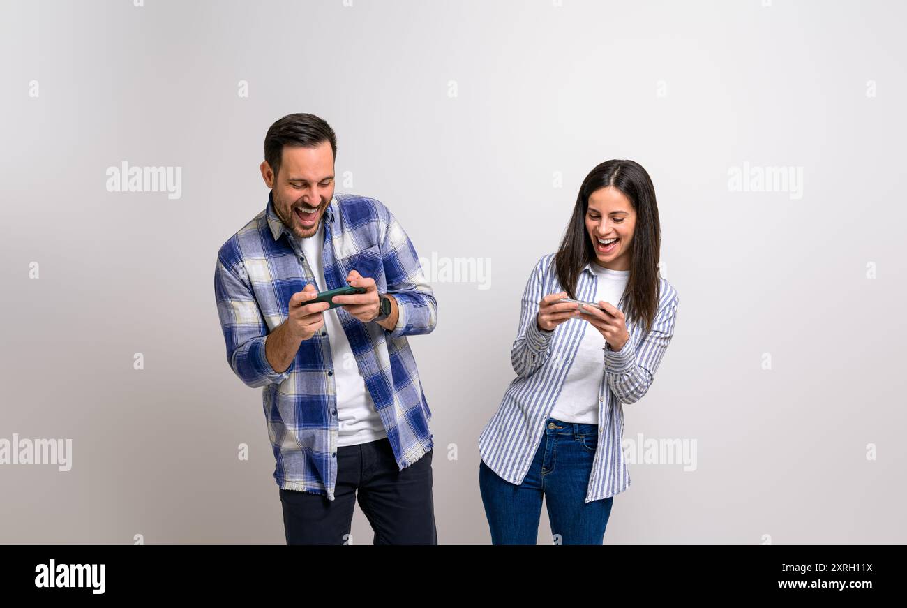 Ecstatic young couple screaming cheerfully while gaming with smart ...
