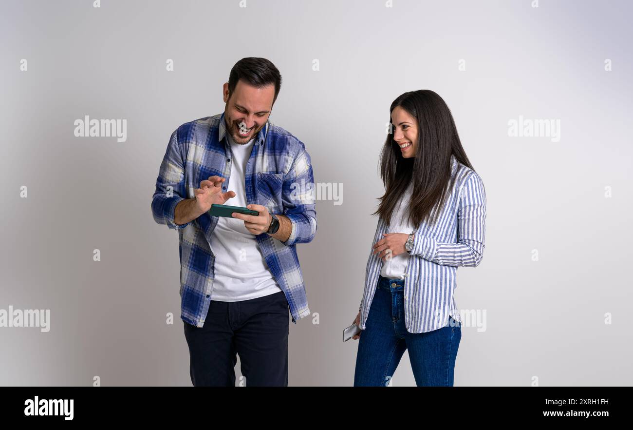 Smiling young girlfriend looking at gamer boyfriend playing video game ...