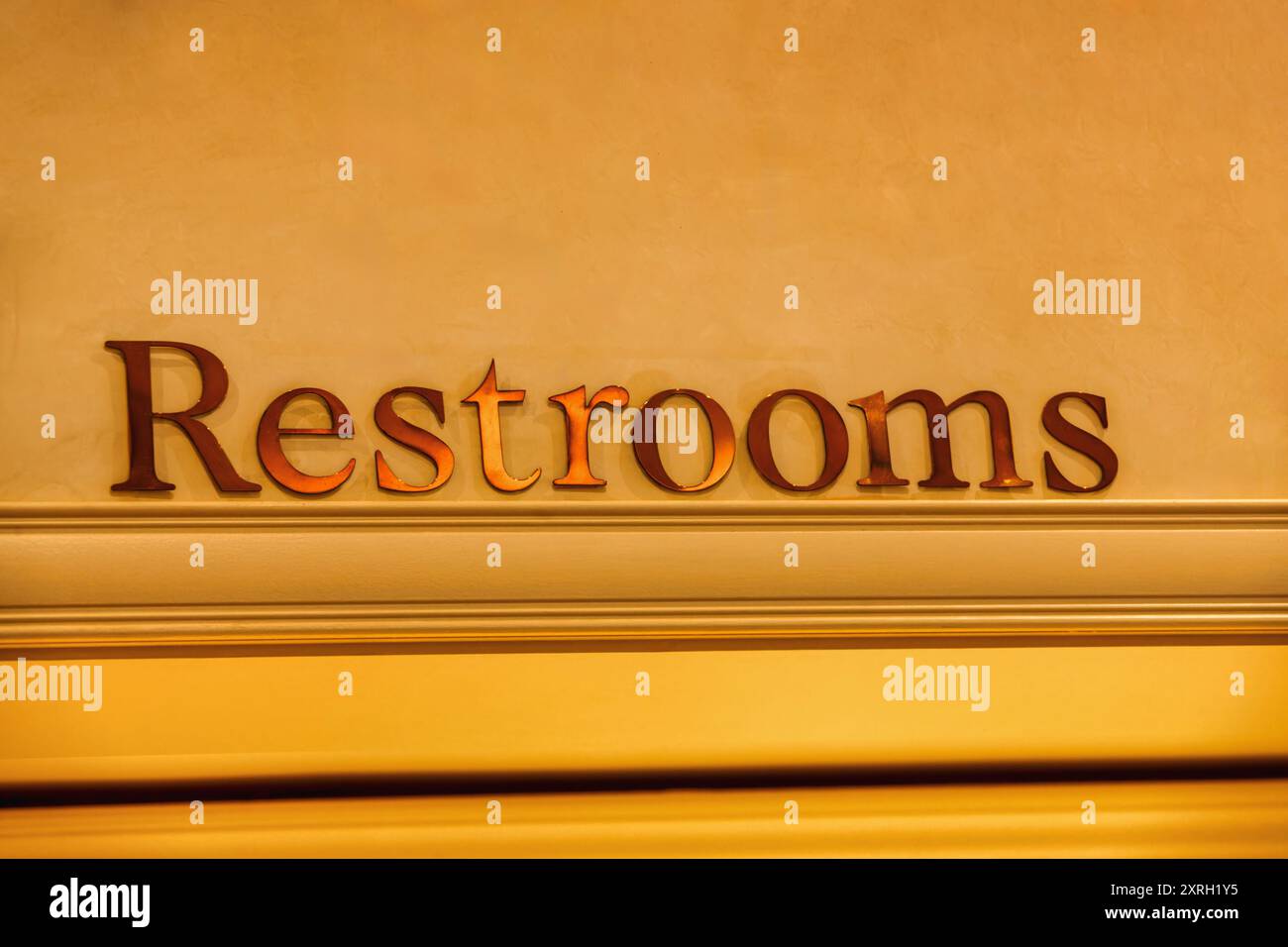 restrooms sign on the wall, font text with golden letters Stock Photo ...