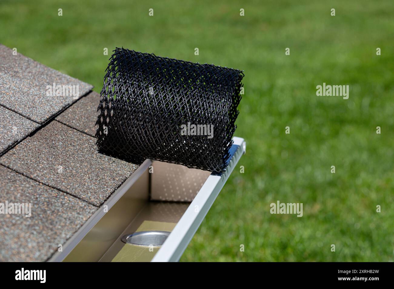 Installing gutter guard mesh screen on rain guttering. Home maintenance ...