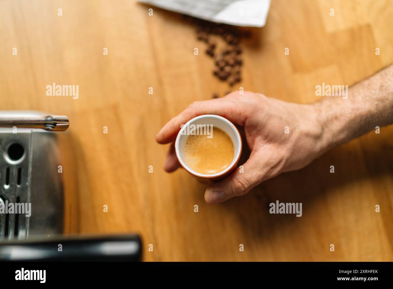 Top view of a hand holding a cup of freshly brewed espresso next to an ...