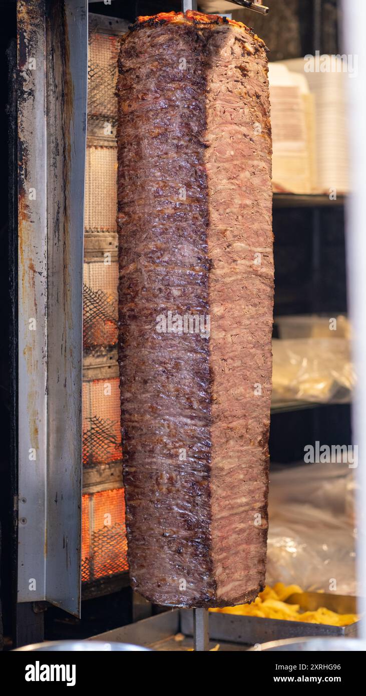 Slicing seasoned meat from a rotating spit for shawarma. Authentic ...