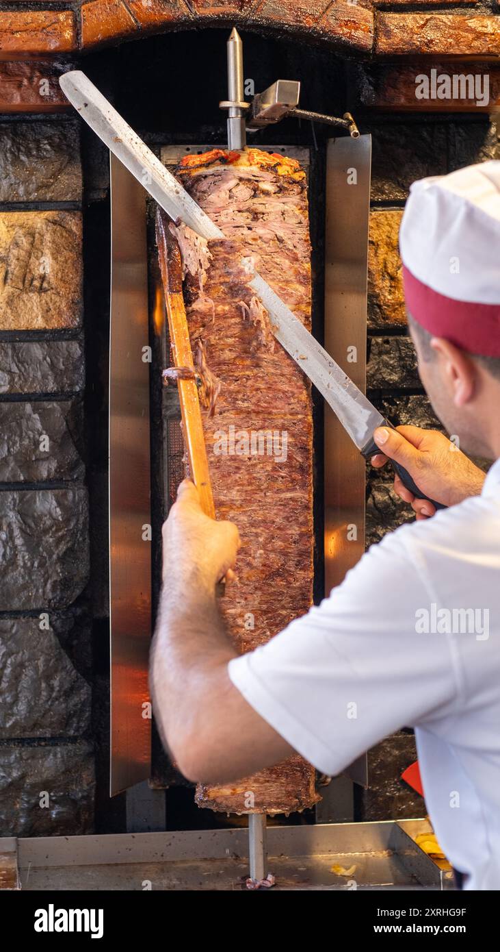 Chef slicing meat for shawarma on a vertical rotisserie. Juicy cuts ...