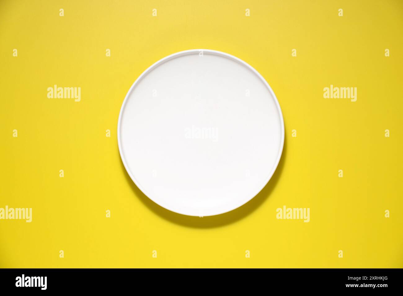 Top down view of a white plate isolated on yellow background with copy ...